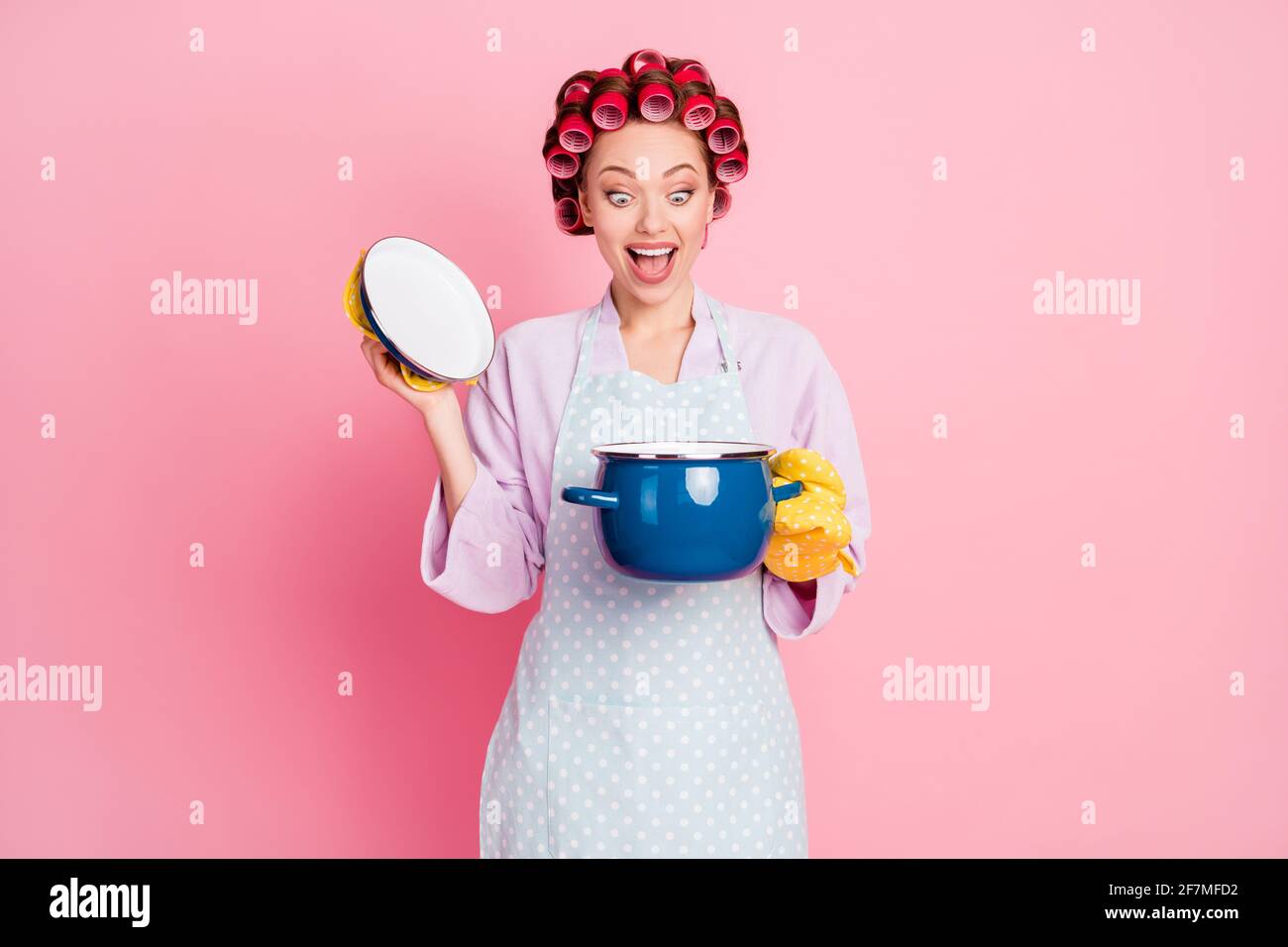 Photo Of Shocked House Wife Wear Dotted Blue Apron Red Rollers Looking