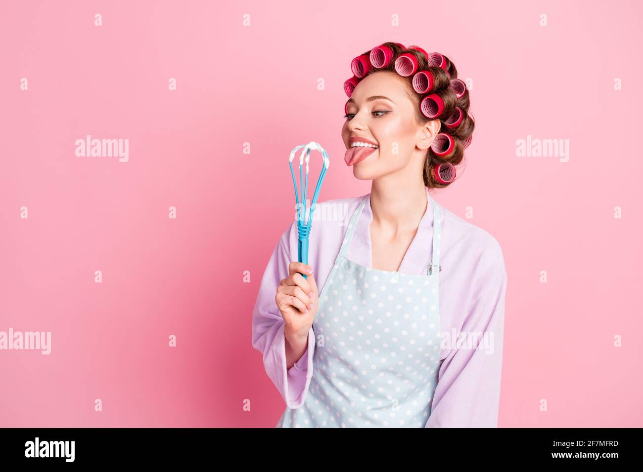 Photo Of Pretty House Wife Wear Dotted Blue Apron Red Rollers Looking