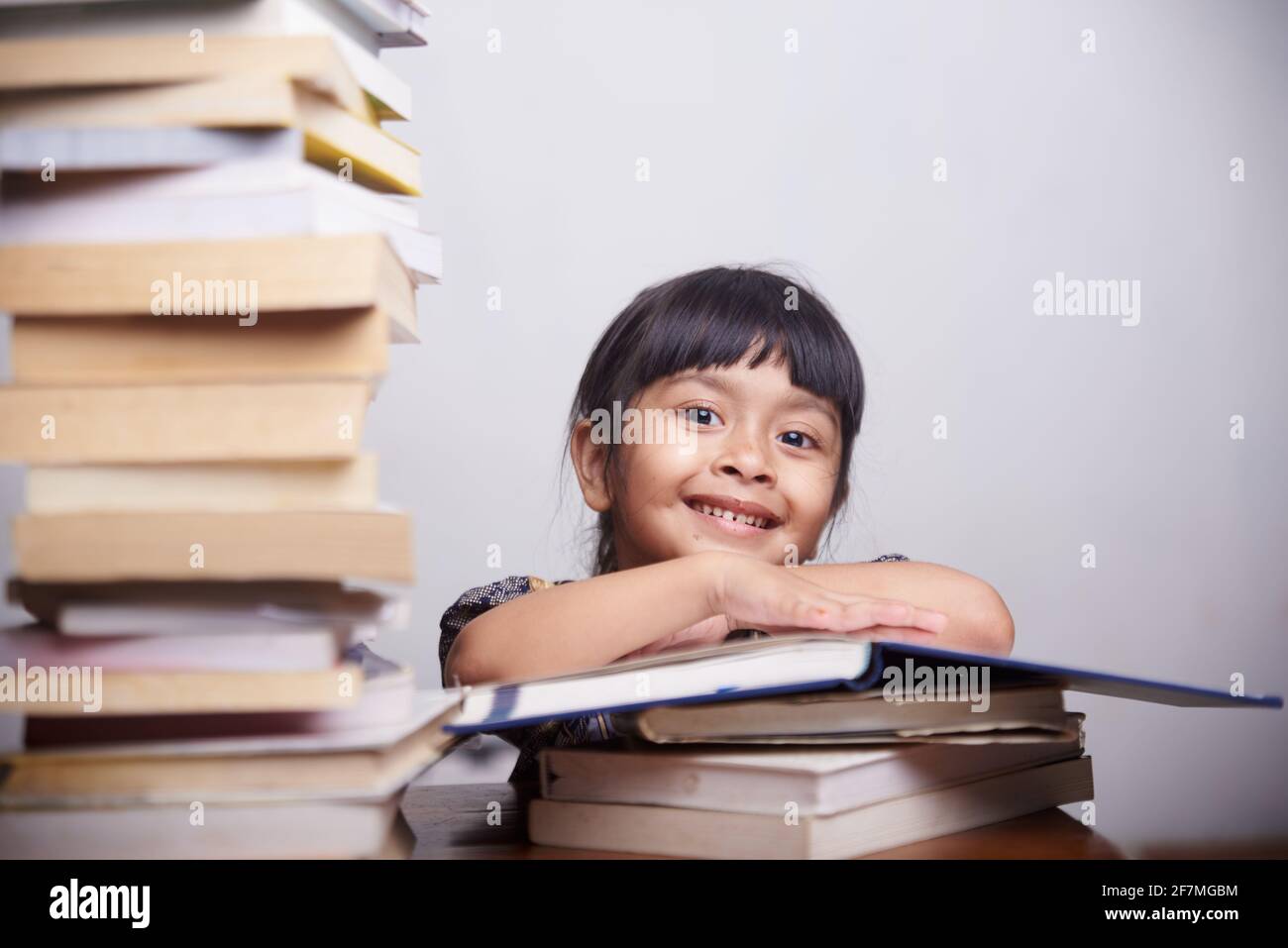 Happy little girl With Dark Hair Reading stack of Book In Library Stock ...