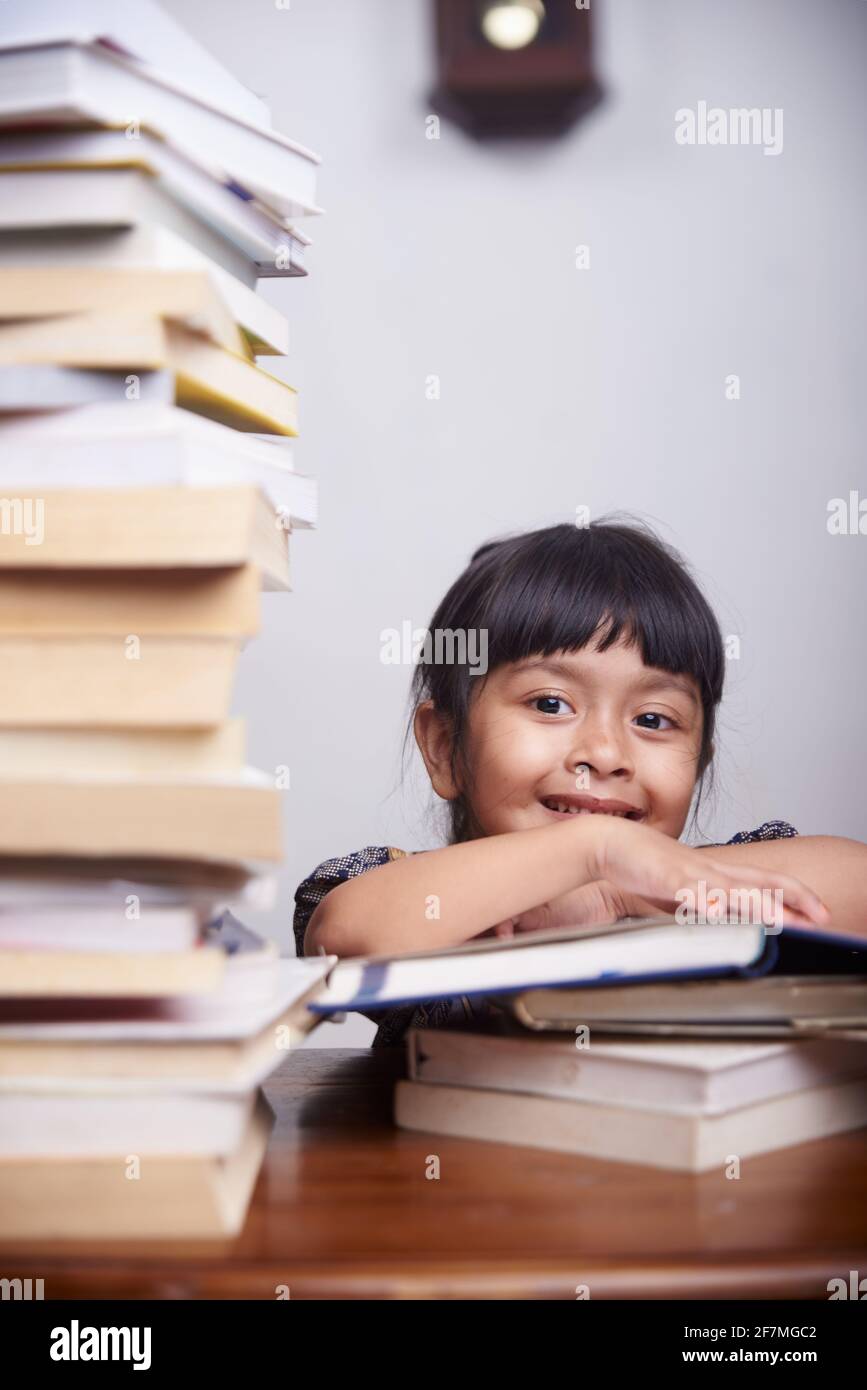 Happy little girl With Dark Hair Reading stack of Book In Library Stock ...