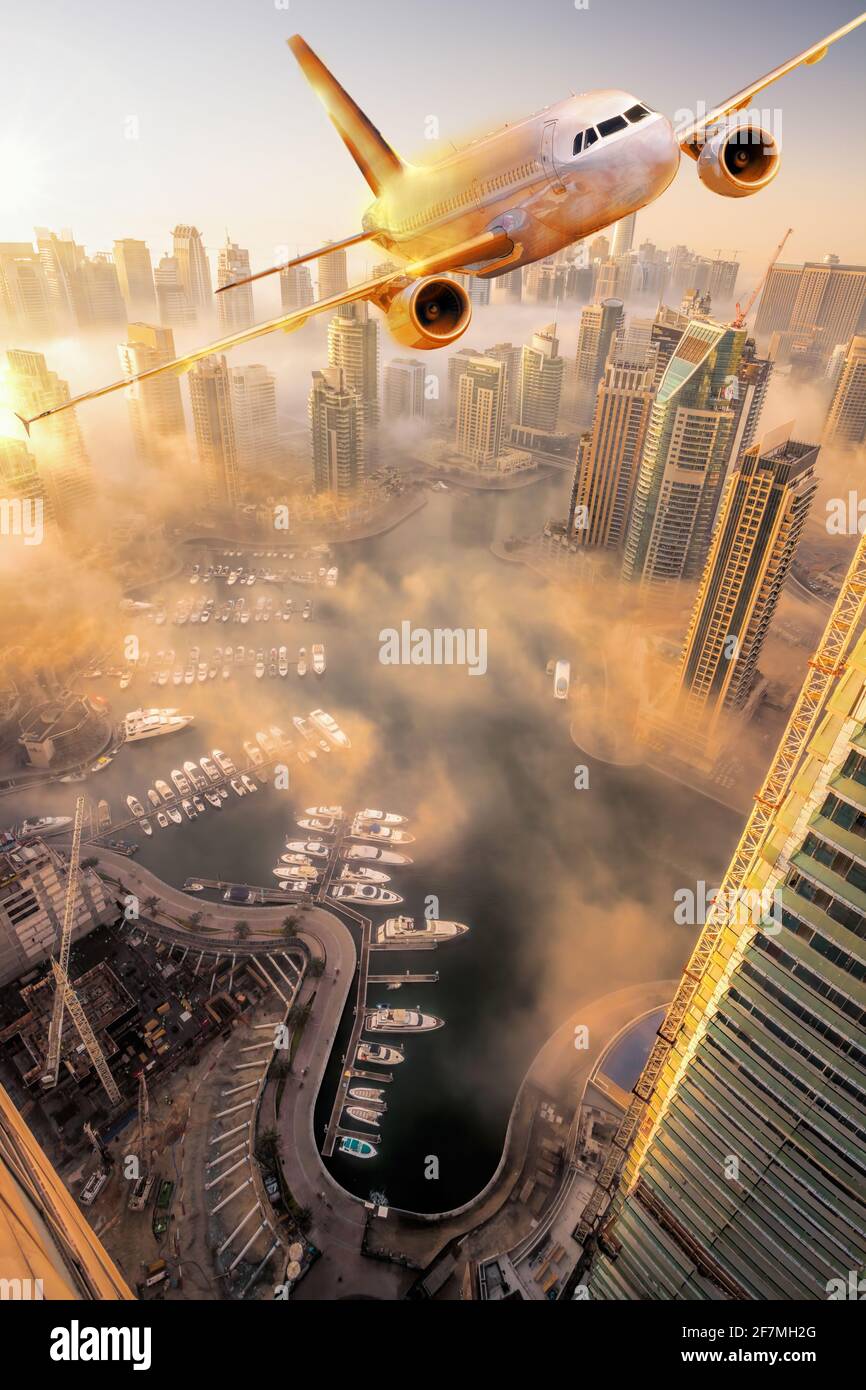 Plane is flying over Dubai Marina against colorful sunset in Dubai city ...