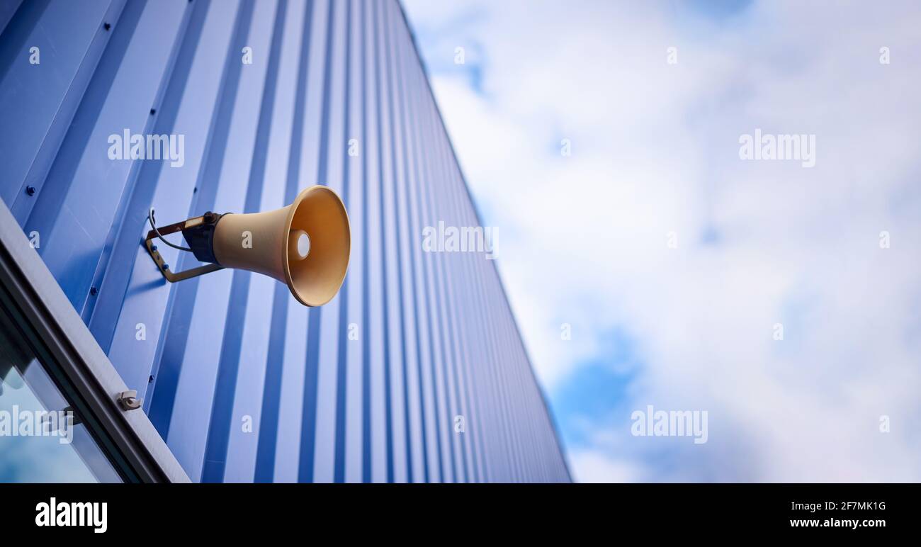 Megaphone hangs on the wall and blue sky with clouds with copy space ...
