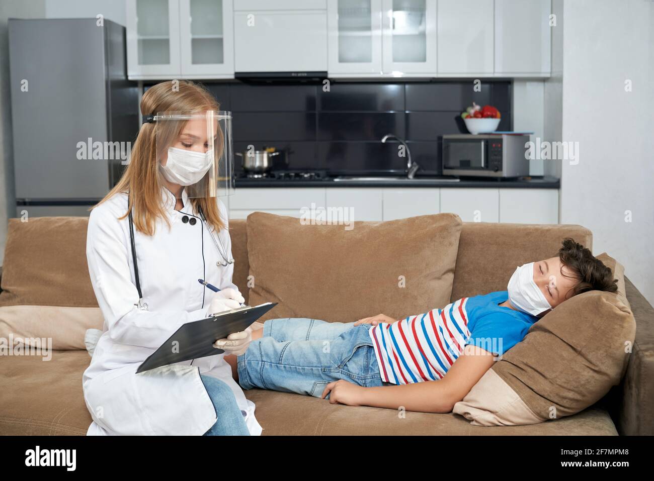 Competent pediatrician in uniform, protective mask and gloves visiting ...