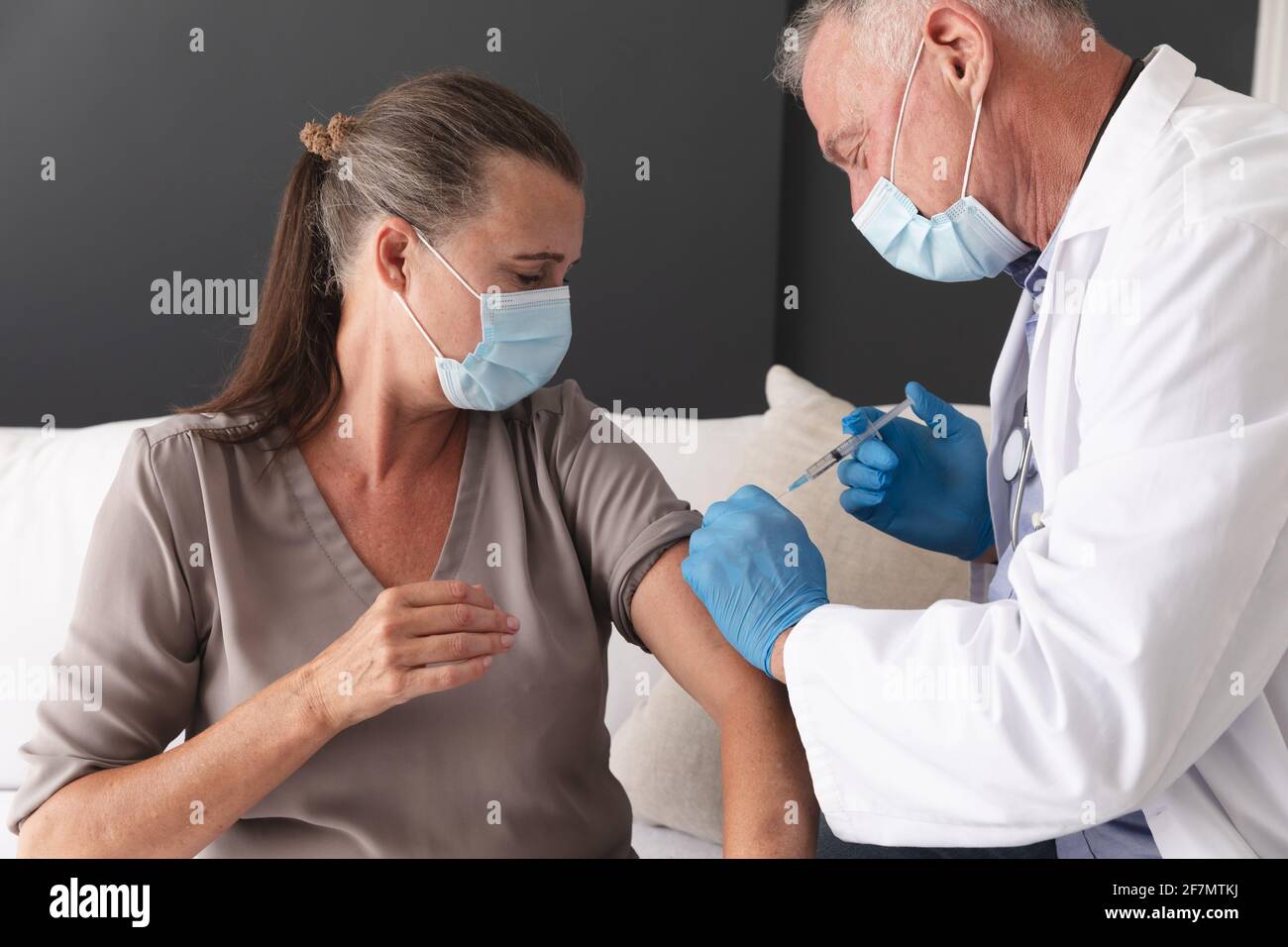 Caucasian senior male doctor giving female patient covid 19 vaccination ...