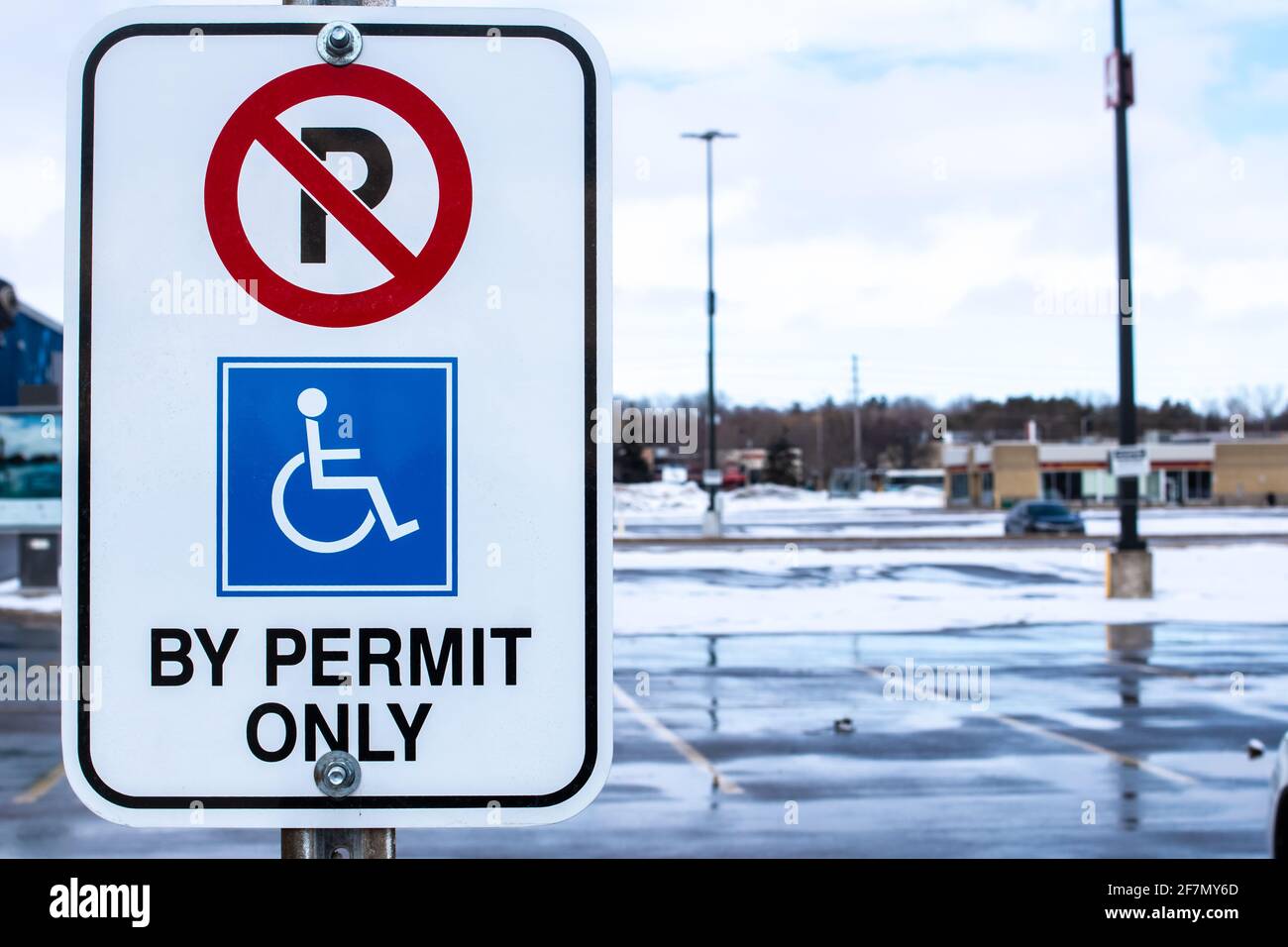 No parking, by permit only sign with the international access symbol ...