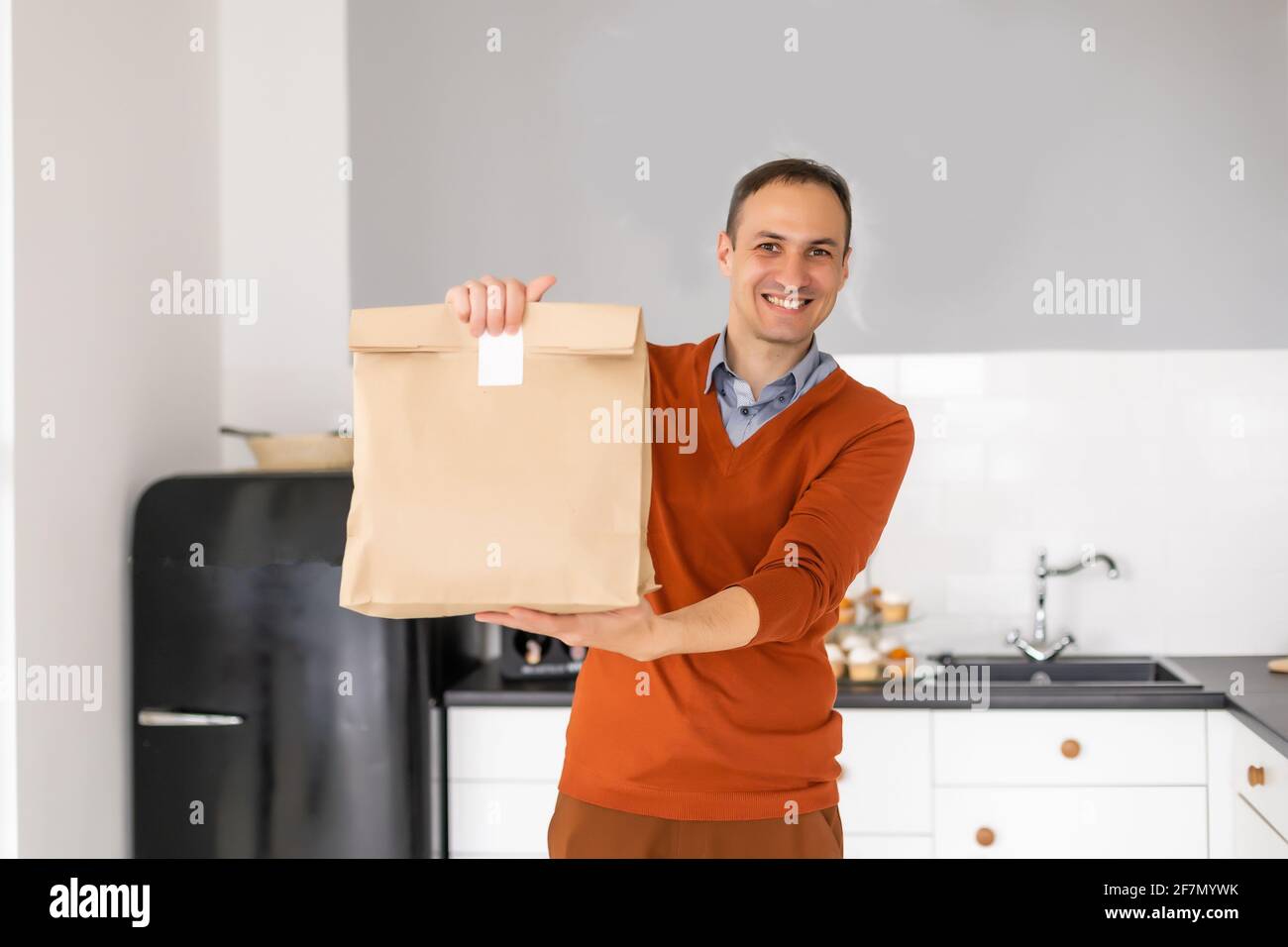 Cheerful delivery man. Happy young courier holding a delivery package ...
