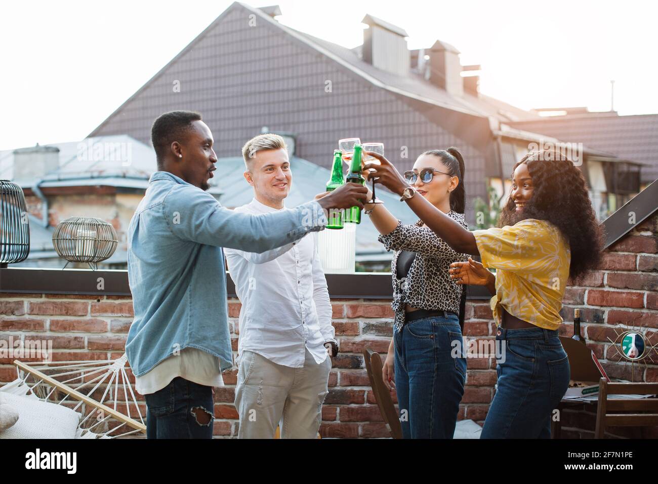 Cheerful young men and women in casual wear toasting with alcoholic ...