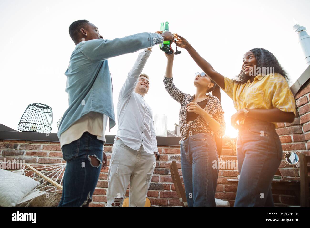 Cheerful young men and women in casual wear toasting with alcoholic ...