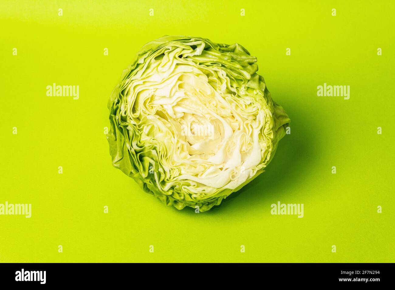 Fresh young cabbage, half a head in bright green background. Modern ...