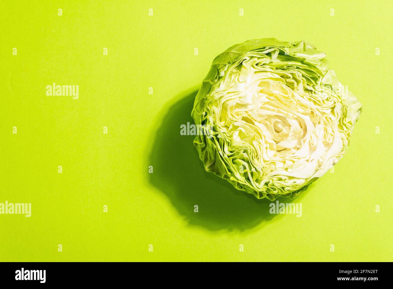 Fresh young cabbage, half a head in bright green background. Modern ...