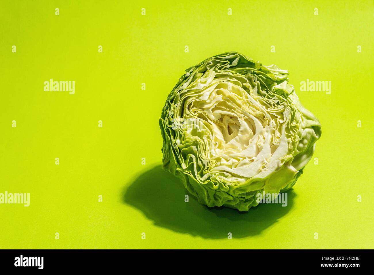 Fresh young cabbage, half a head in bright green background. Modern ...