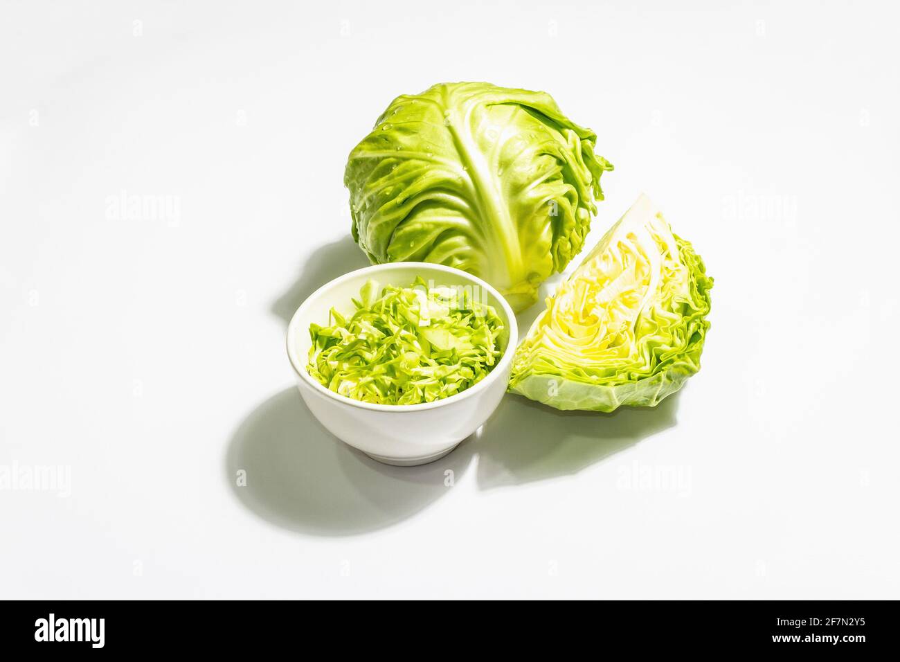 Fresh young shredded cabbage, whole head and cut piece isolated in ...