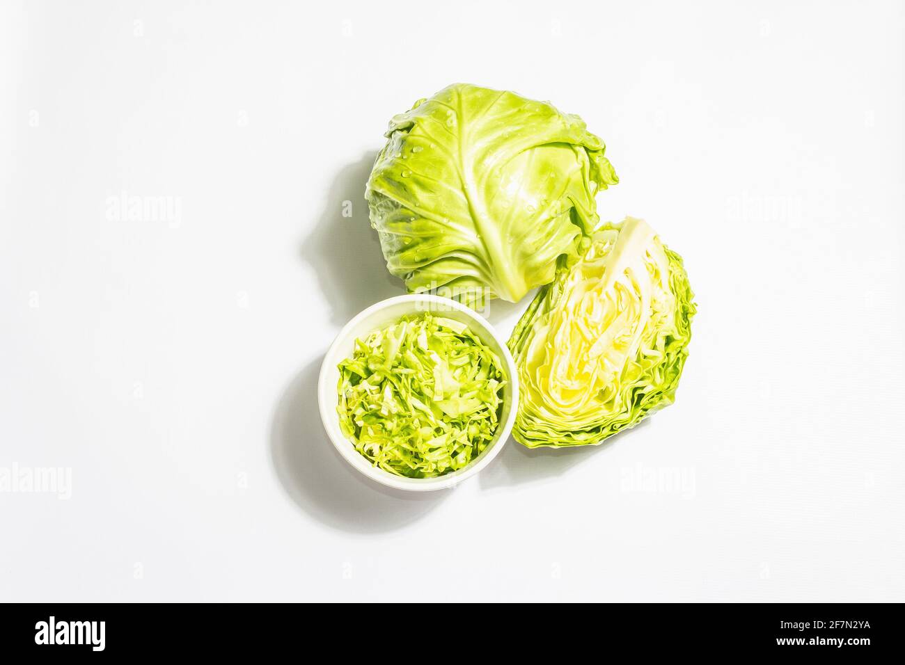 Fresh young shredded cabbage, whole head and cut piece isolated in ...