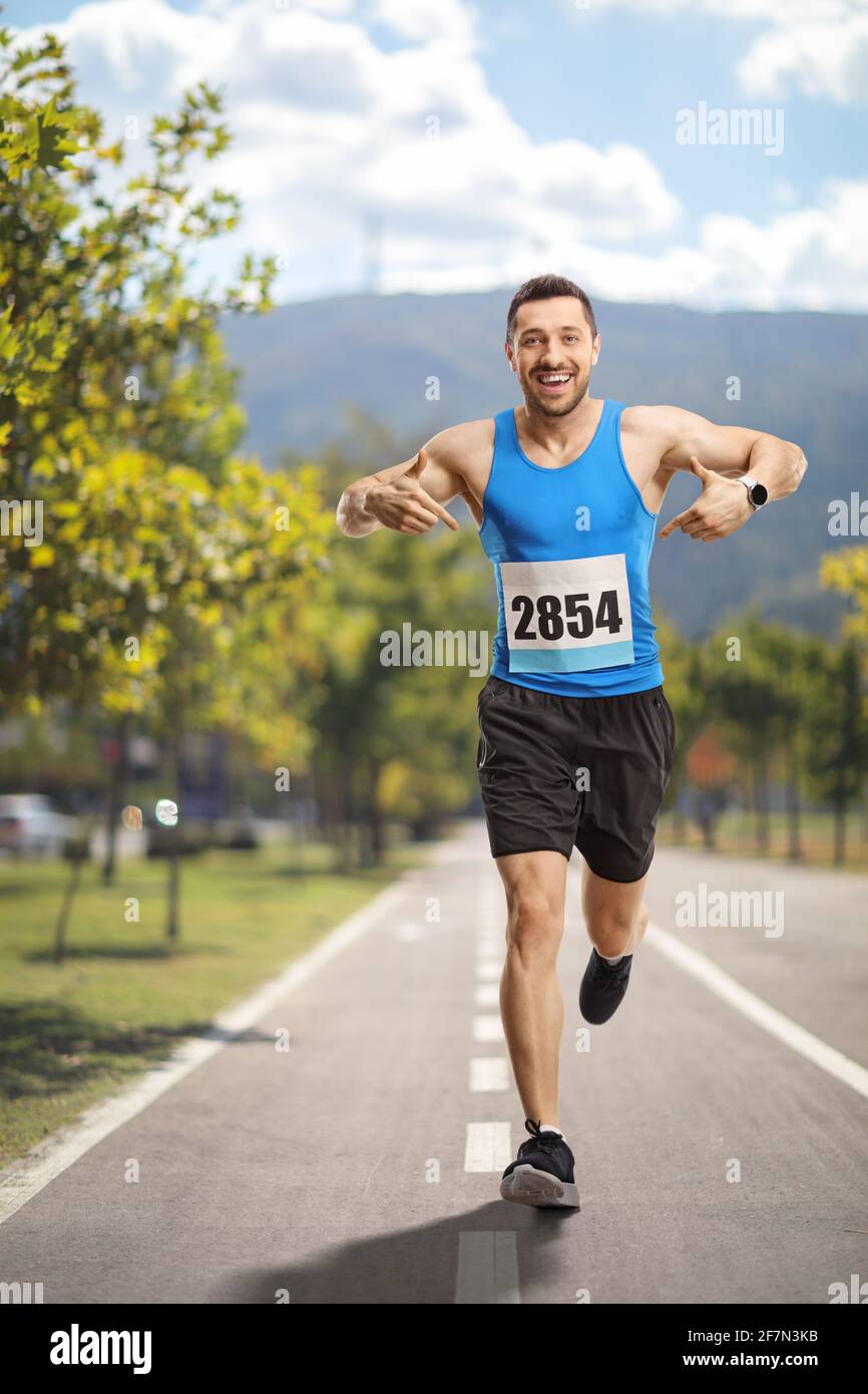 Full length portrait of a male athlete running on a track and pointing ...