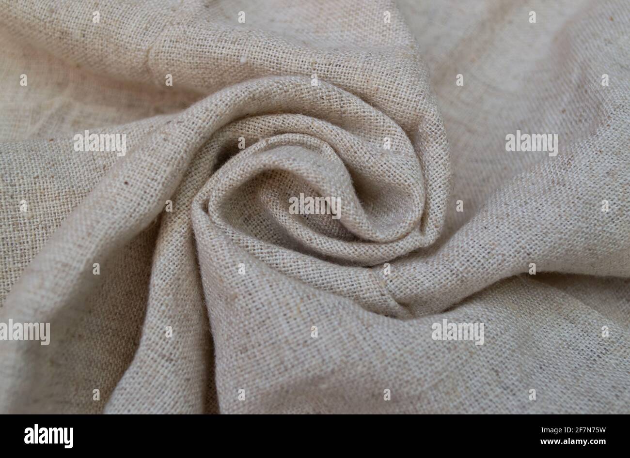 Natural linen fabric, twisted in the center into a spiral. Textile ...