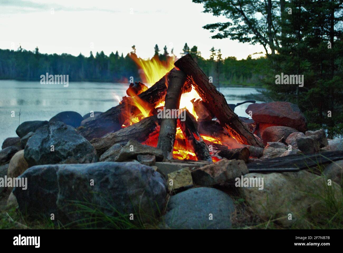 camp fire burning in a fire pit next to the lake Stock Photo - Alamy