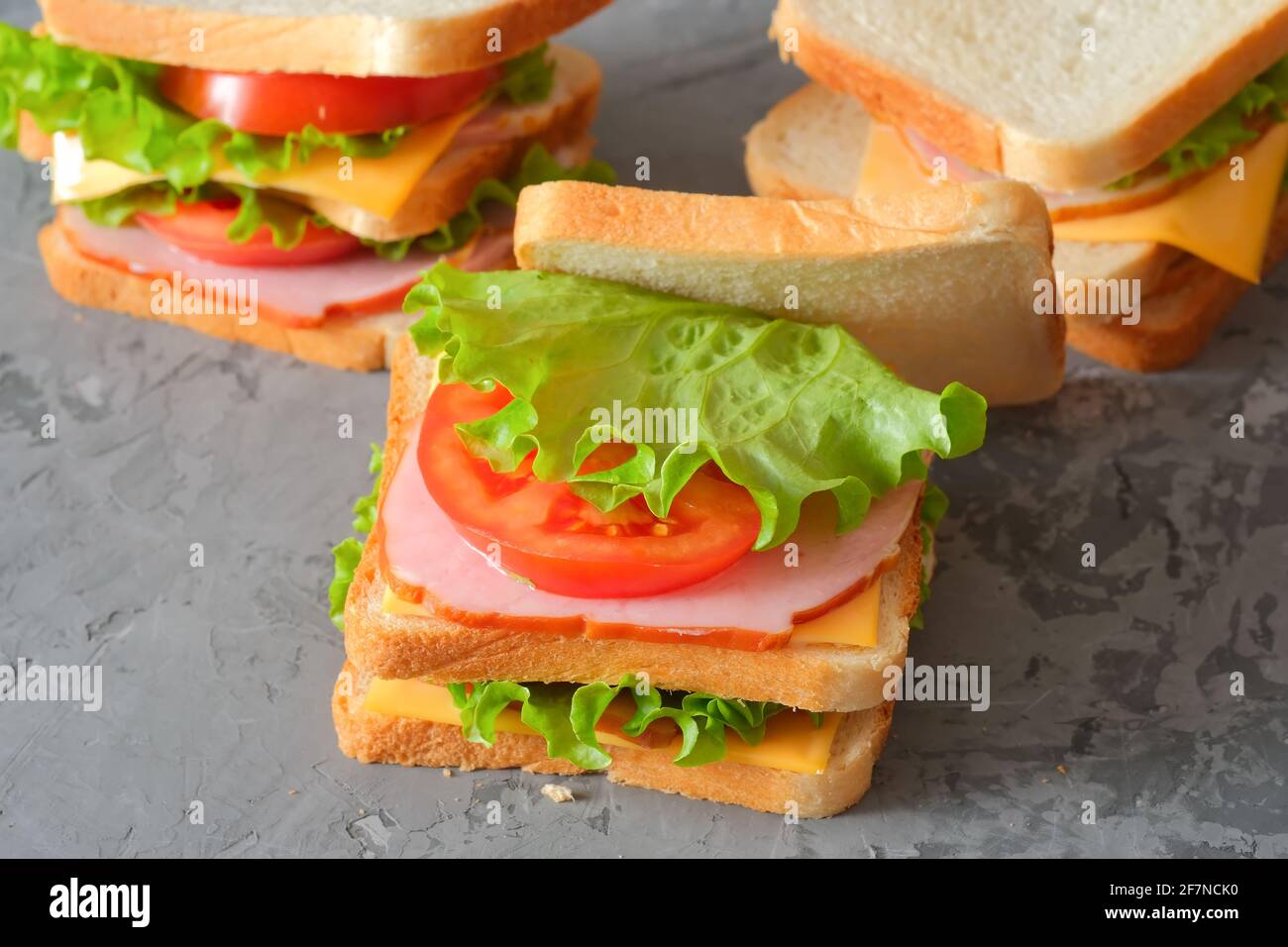 Three tasty sandwiches on rustic wooden background Stock Photo - Alamy