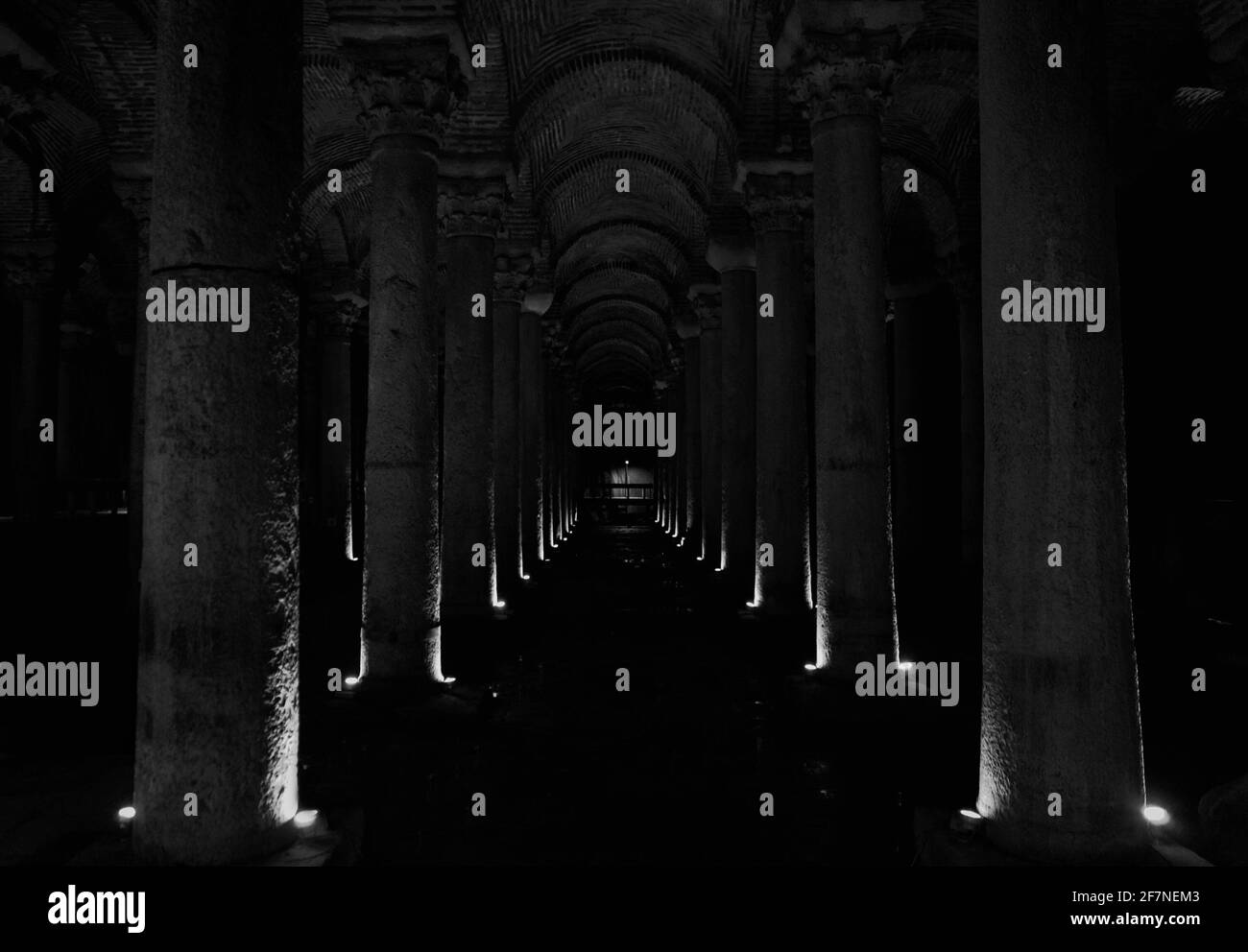 A dark colonnade of an ancient chamber with columns lit with faint ...