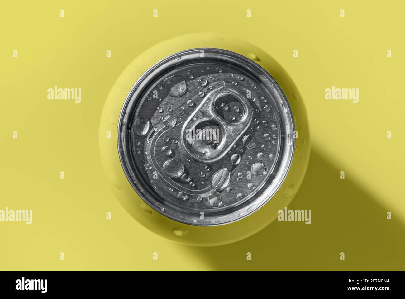 Yellow pop can with water drops casting shadow on yellow background ...
