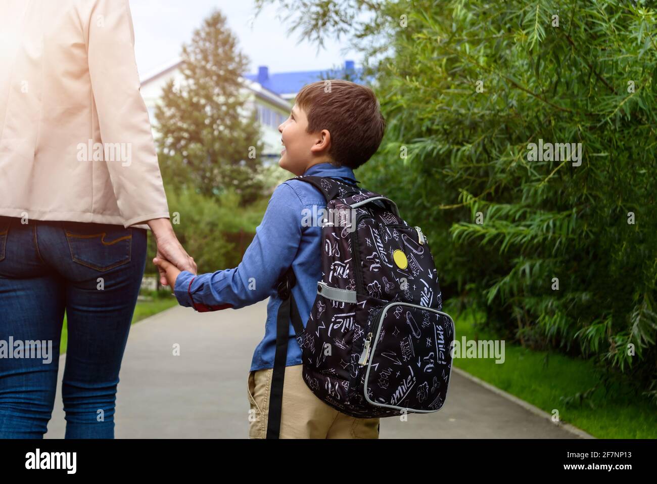 Parent and pupil of primary school go hand in hand. Woman and boy with ...