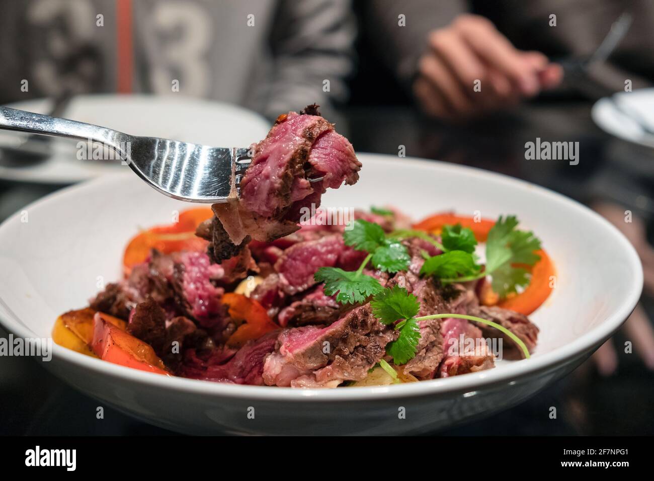 Fork dipping grilled beef steak sliced on dining table Stock Photo - Alamy