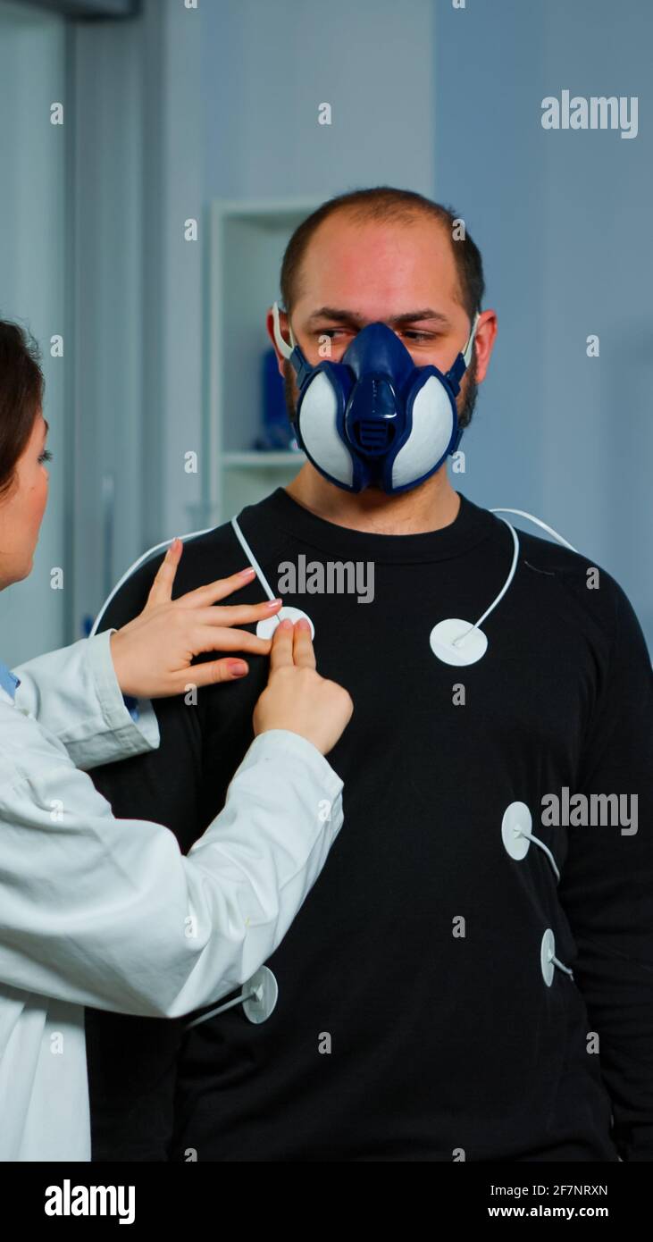 Woman researcher preparing patient for endurance test using electrodes ...