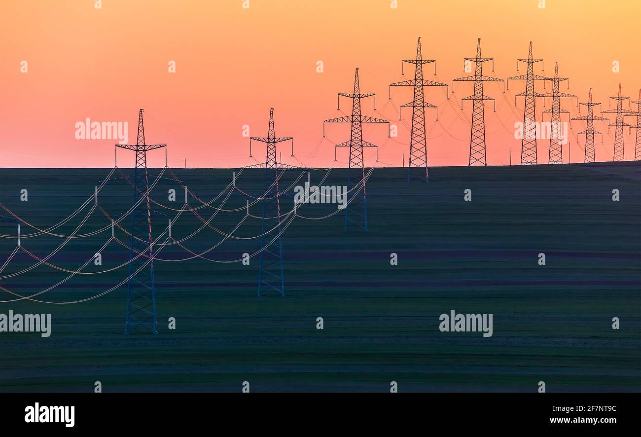 Power lines on a field at sunset Stock Photo - Alamy