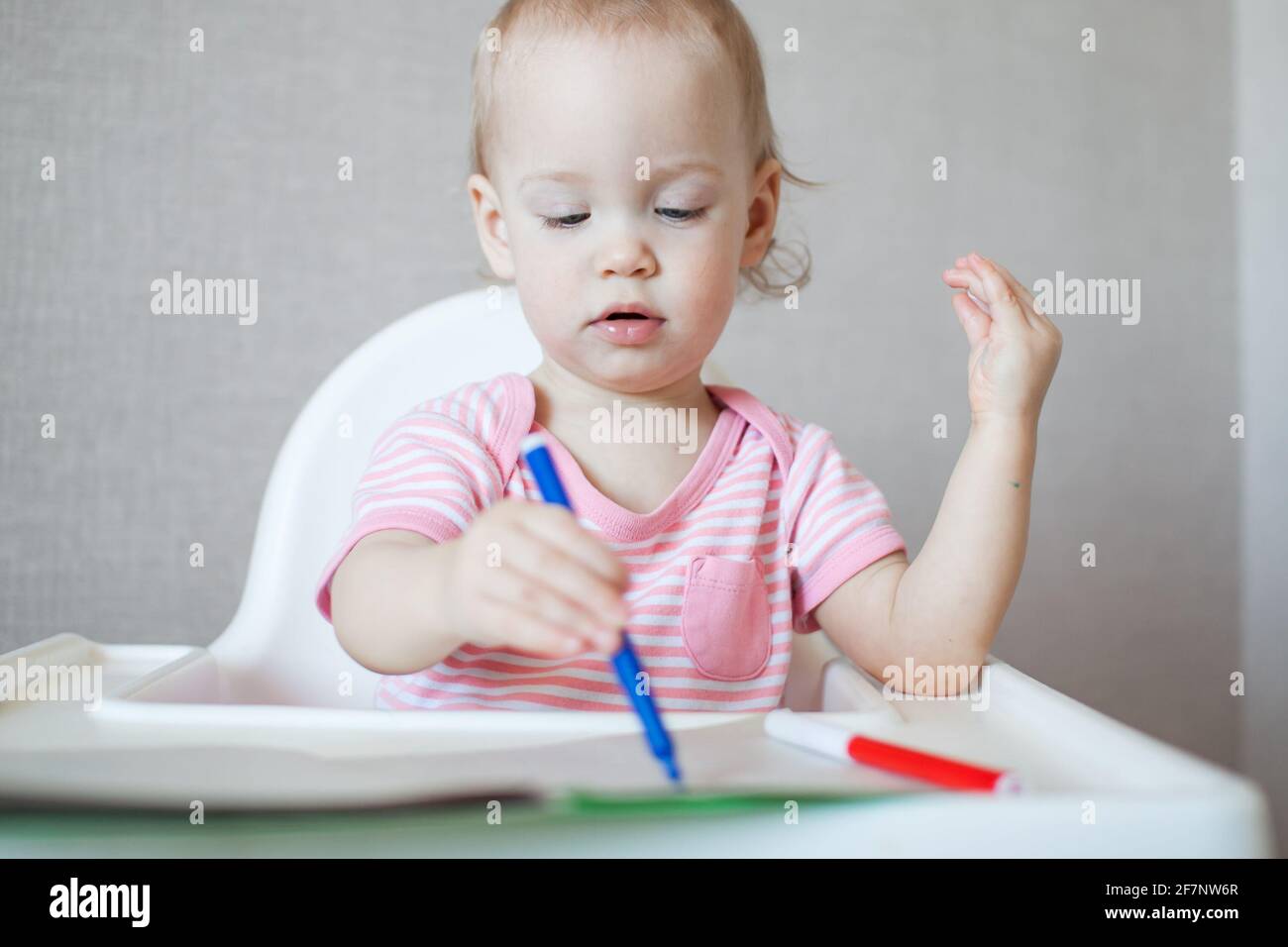 A little girl tries to draw with felt-tip pens with pleasure and ...