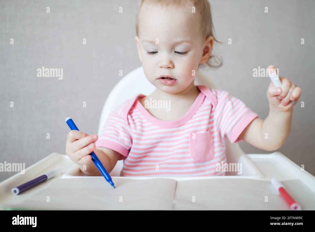 A little girl tries to draw with felt-tip pens with pleasure and ...