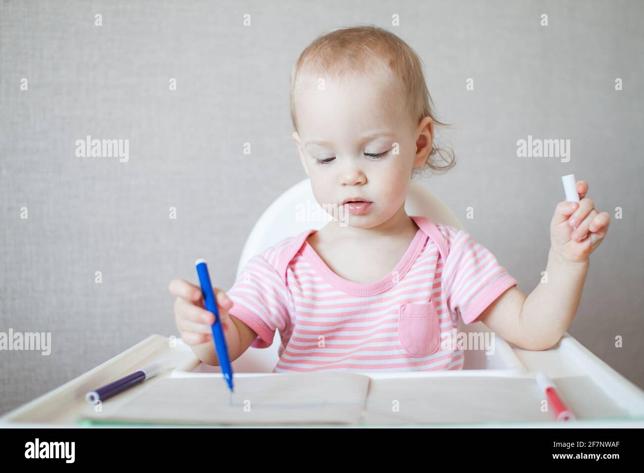 A little girl tries to draw with felt-tip pens with pleasure and ...