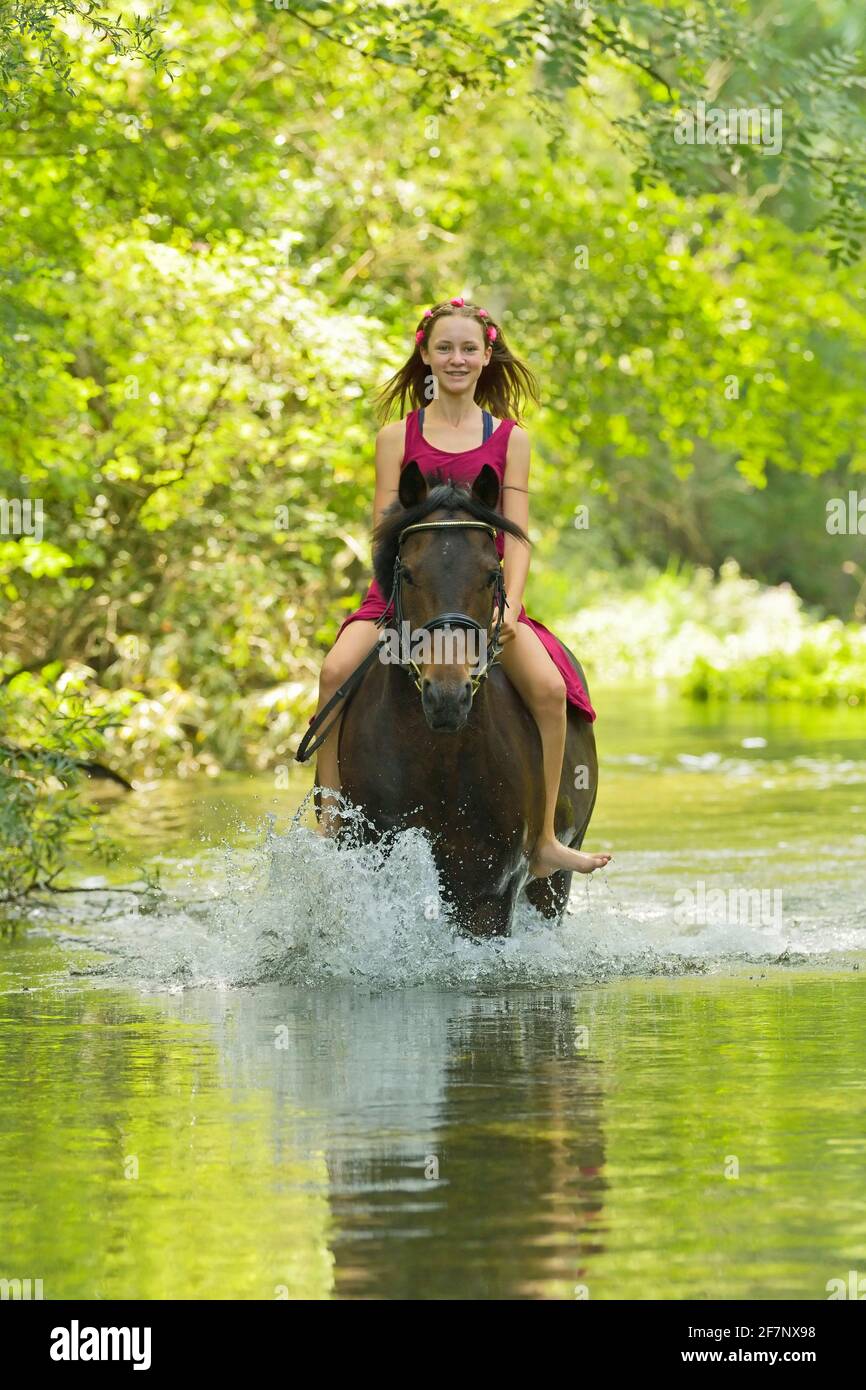 Girl on back of German pony riding bareback in a stream Stock Photo - Alamy