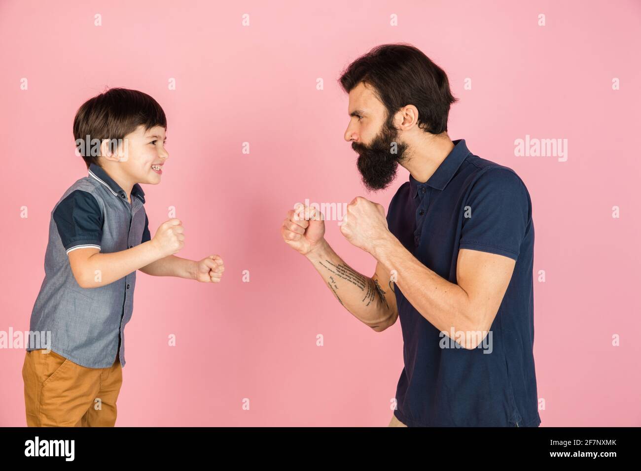 Caucasian man and little boy, father and son isolated over pink ...