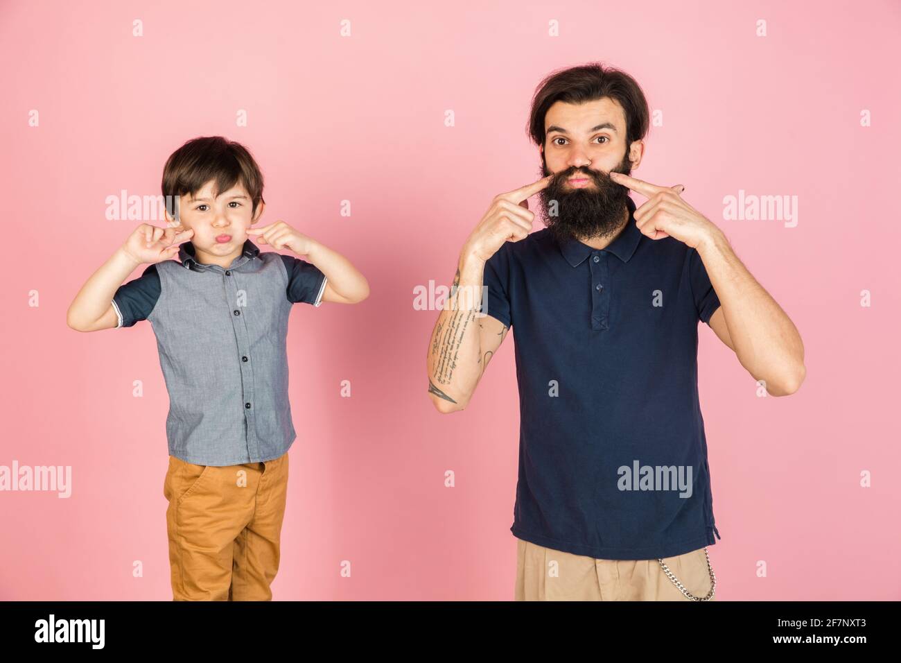 Caucasian man and little boy, father and son isolated over pink ...