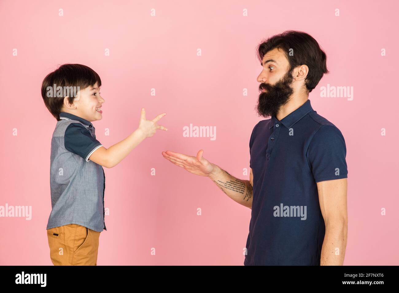 Two people, man and little boy, father and son isolated over pink ...