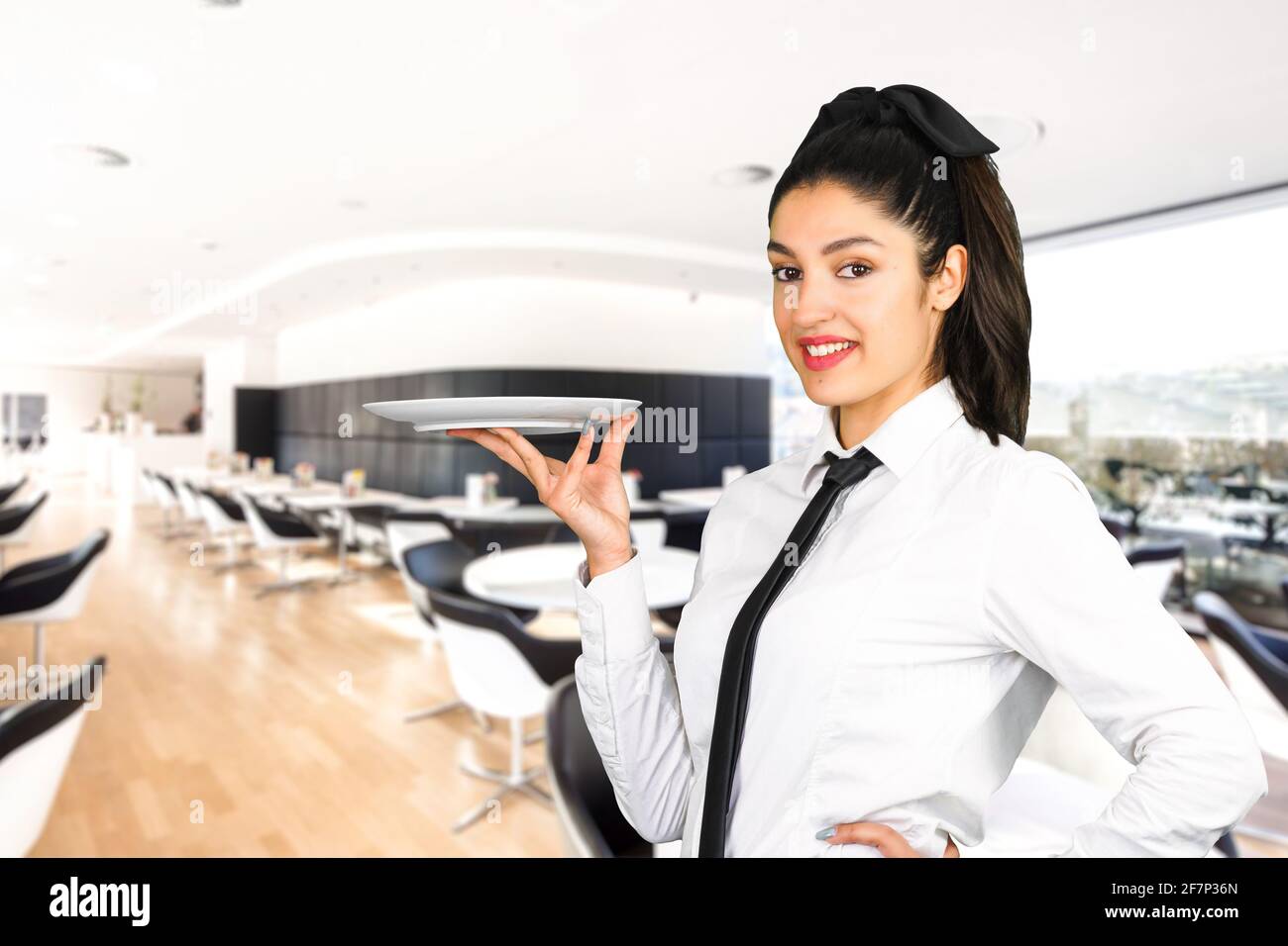 A waiter girl with empty plate poses in front of the dining room ...