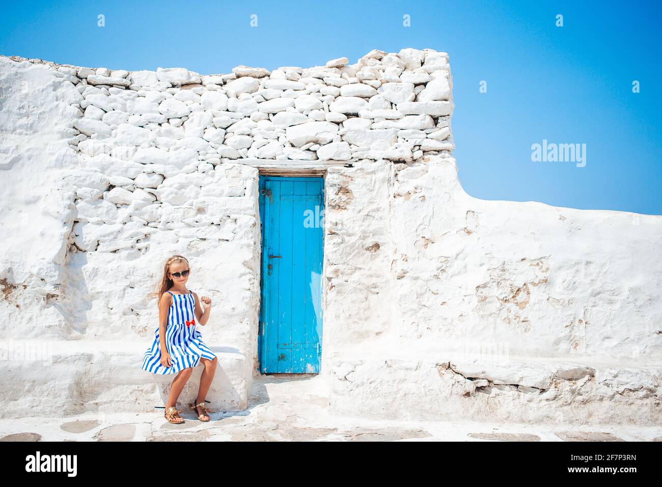 Adorable little girl at old street of typical greek traditional village ...
