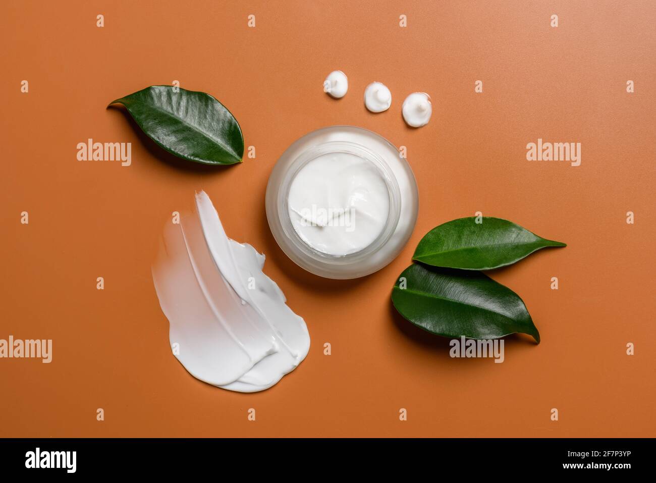 Glass skin cream jar on brown background with smear or swatch and ...