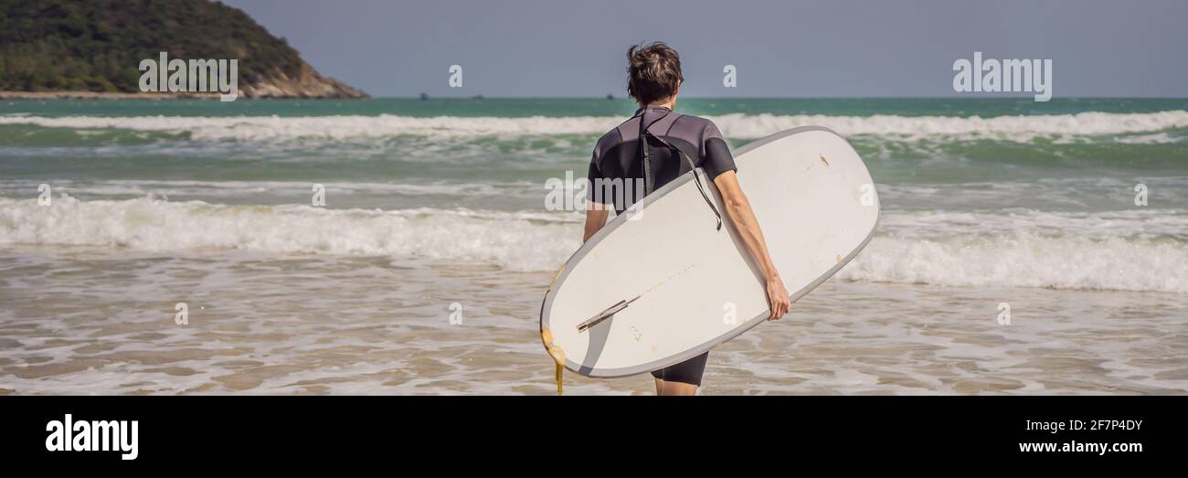 BANNER, LONG FORMAT Young surfer standing agains the ocean looking the ...