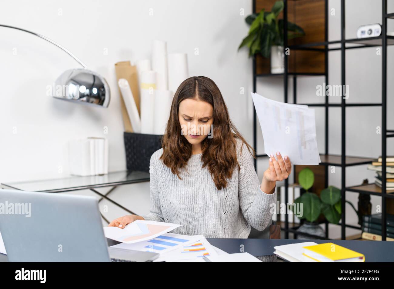 Busy and confident young female office employee doing paperwork sitting ...