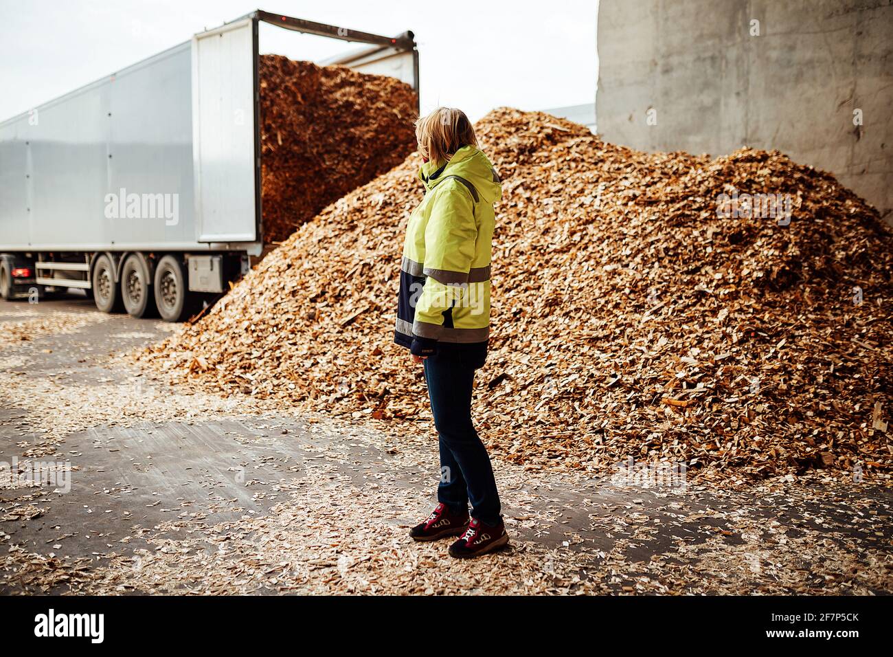 a worker in overalls stands with his back to the wood warehouse. a lot ...
