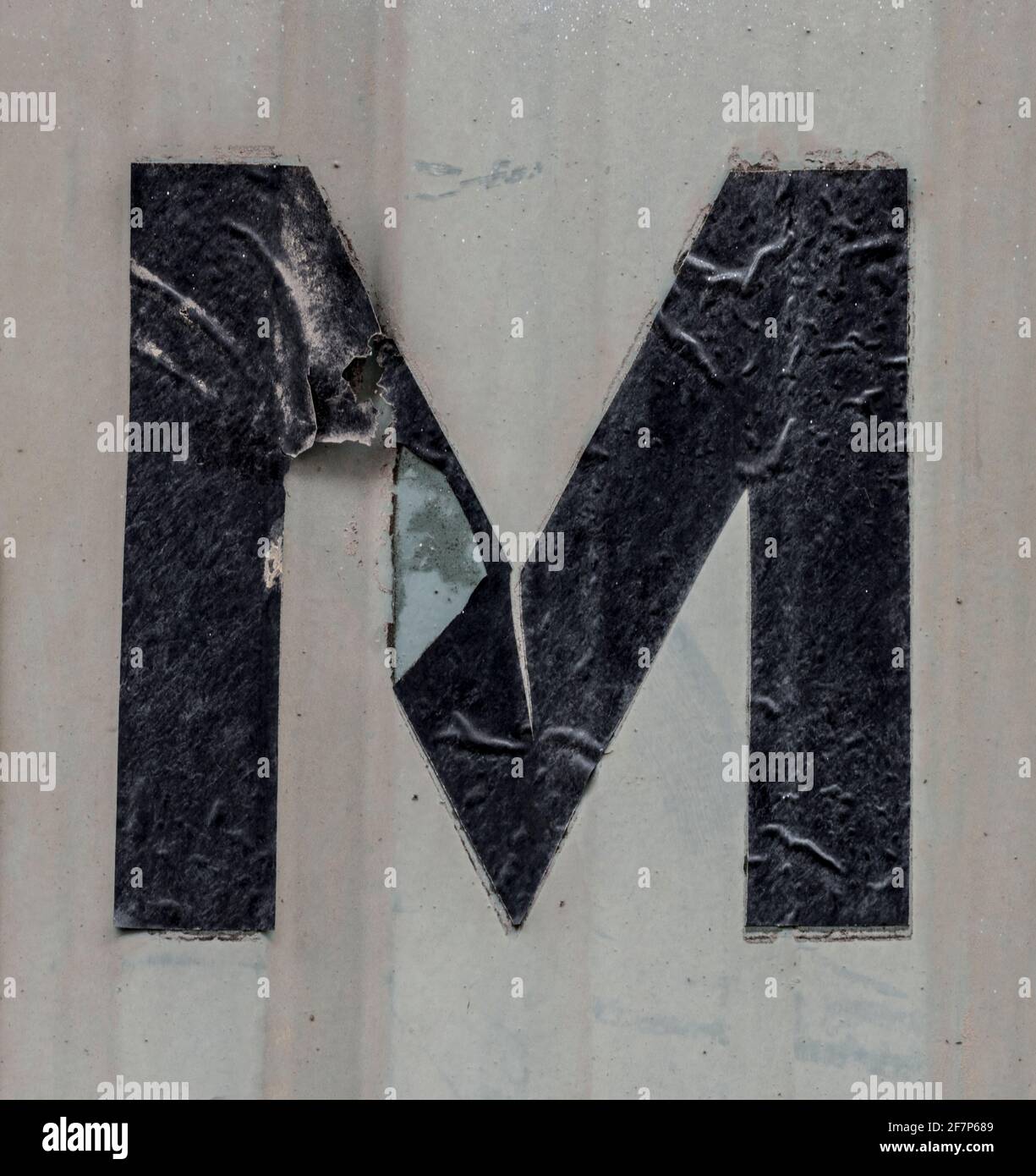 Peeling adhesive letter M Stock Photo - Alamy