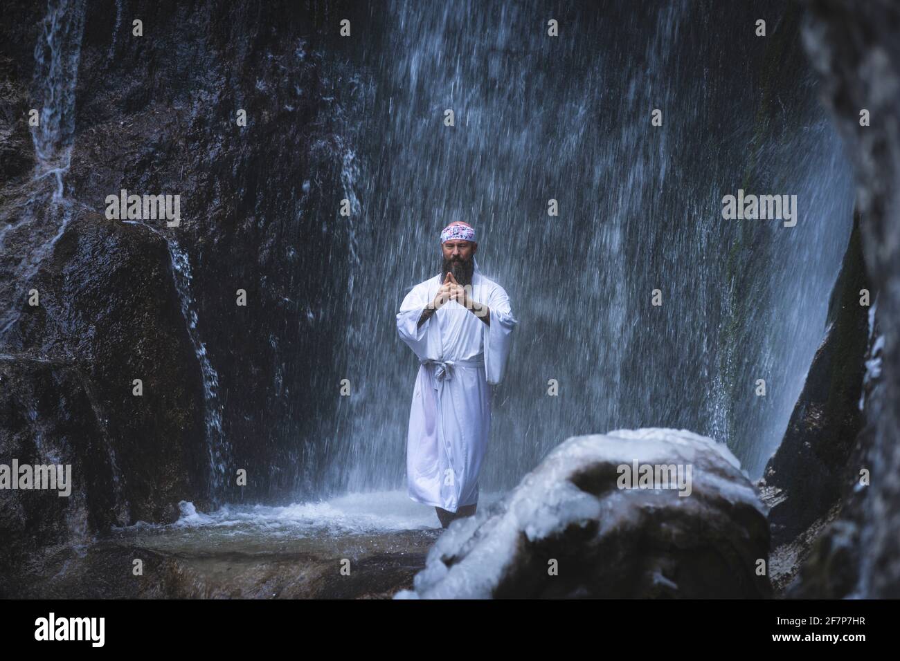 Man in traditional Japanese shugendo outfit doing waterfall meditation ...