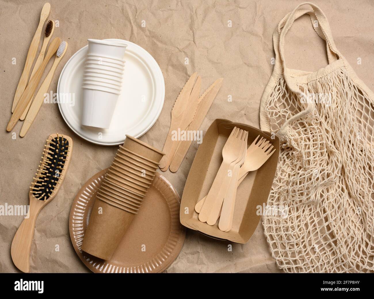 white string bag with disposable paper dishes and wooden forks on brown ...