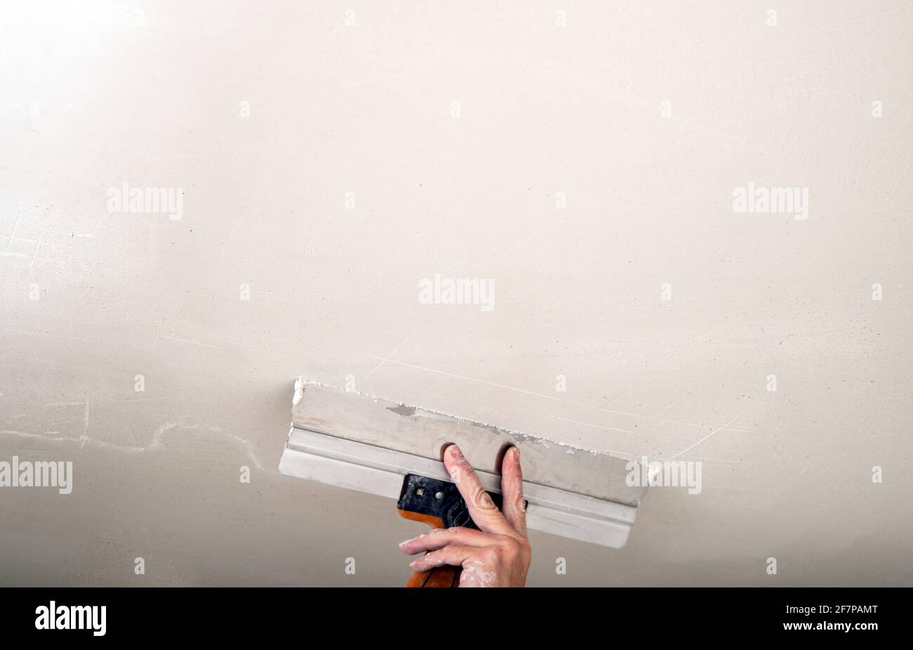 Hand of builder worker spacks ceiling with putty plaster aligning ...