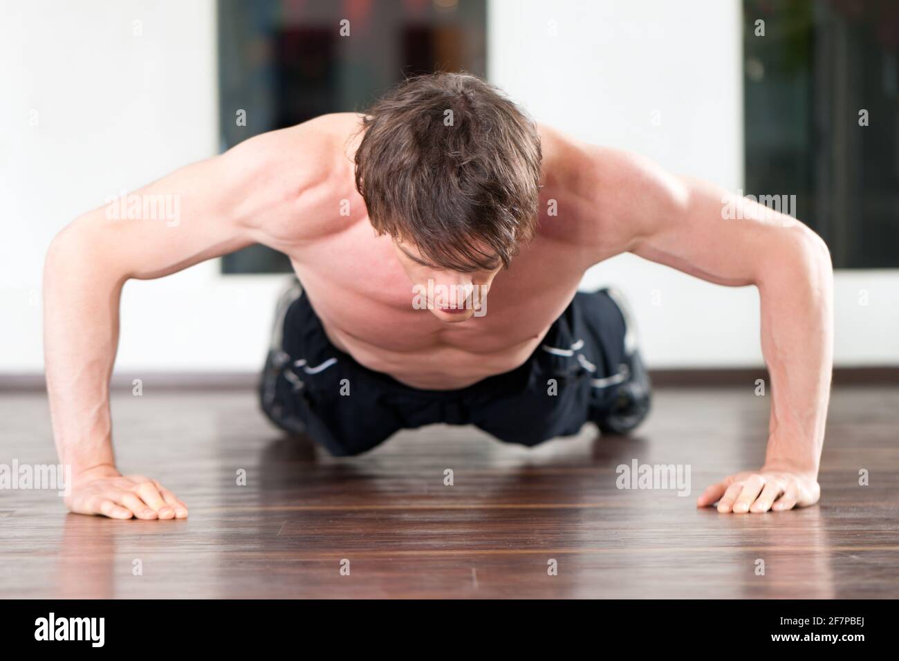 Muscular man exercising by doing pushups in a gym Stock Photo - Alamy