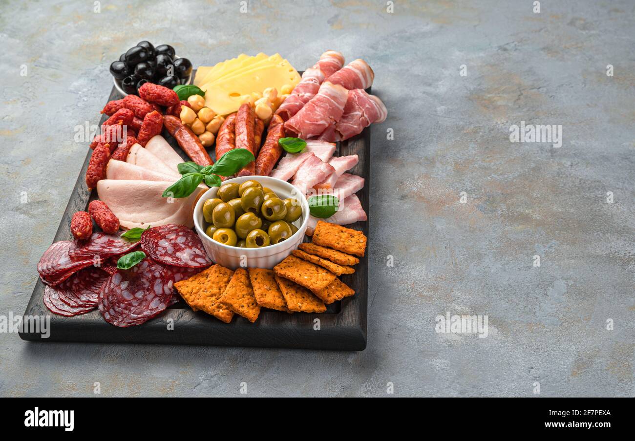 Meat and cheese assortment on a rectangular board on a gray concrete ...