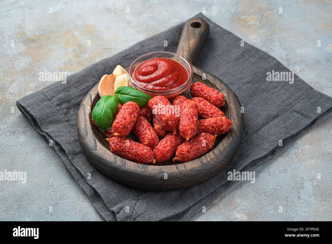 Mini sausages with sauce, garlic and basil on a gray background. Side ...