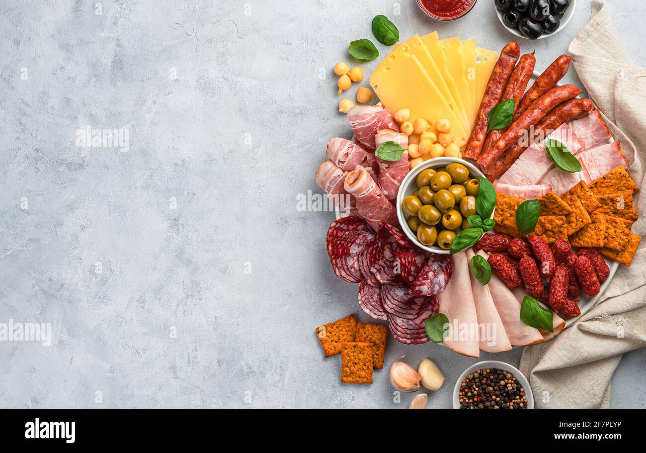 Meat and cheese snacks are sliced and laid out on a round board with ...