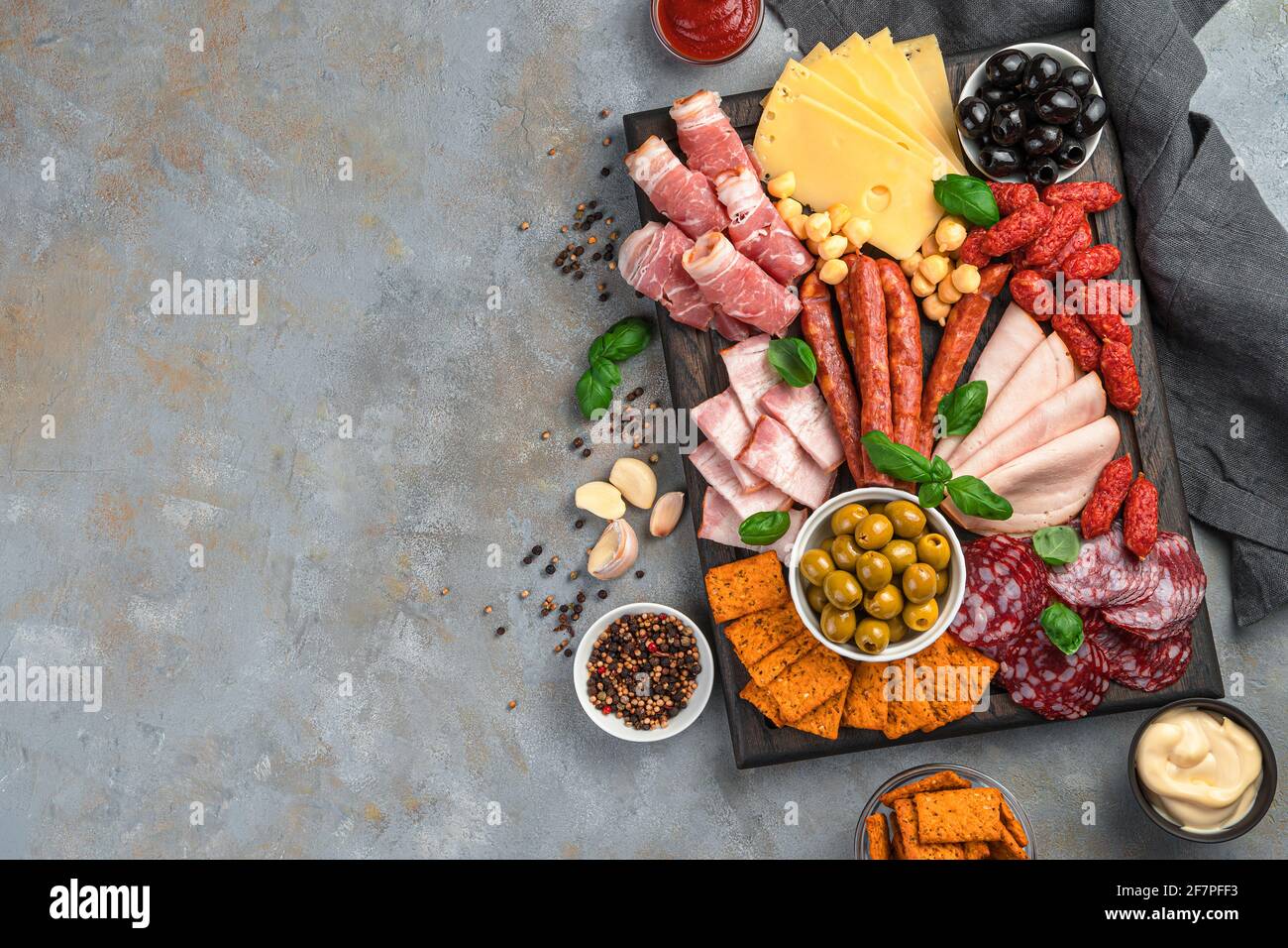 Meat delicacies, cheese, olives, sauces and crackers on a gray ...