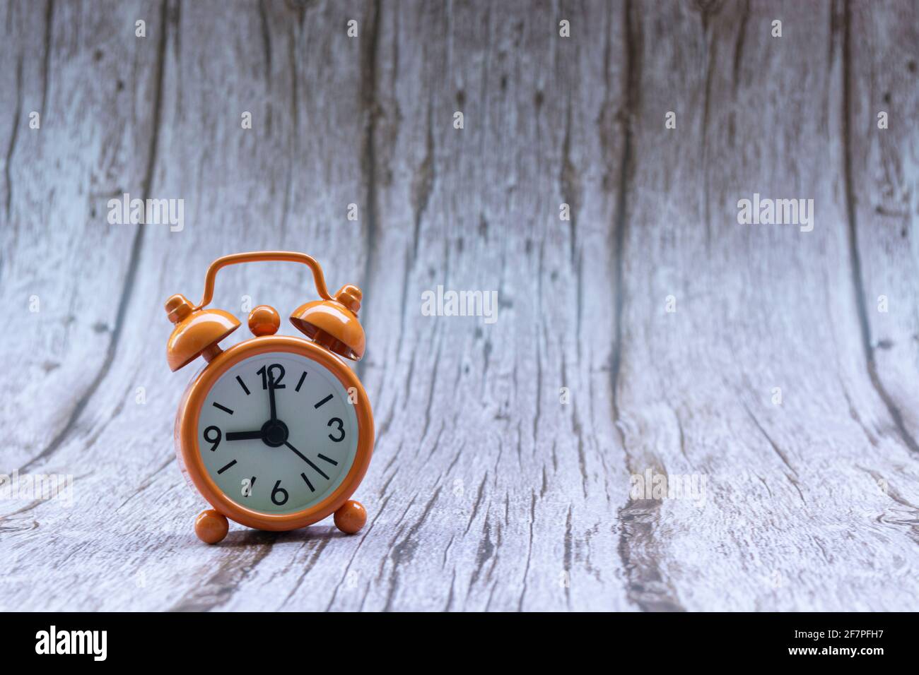 Orange old retro style alarm clock on wooden background Stock Photo - Alamy